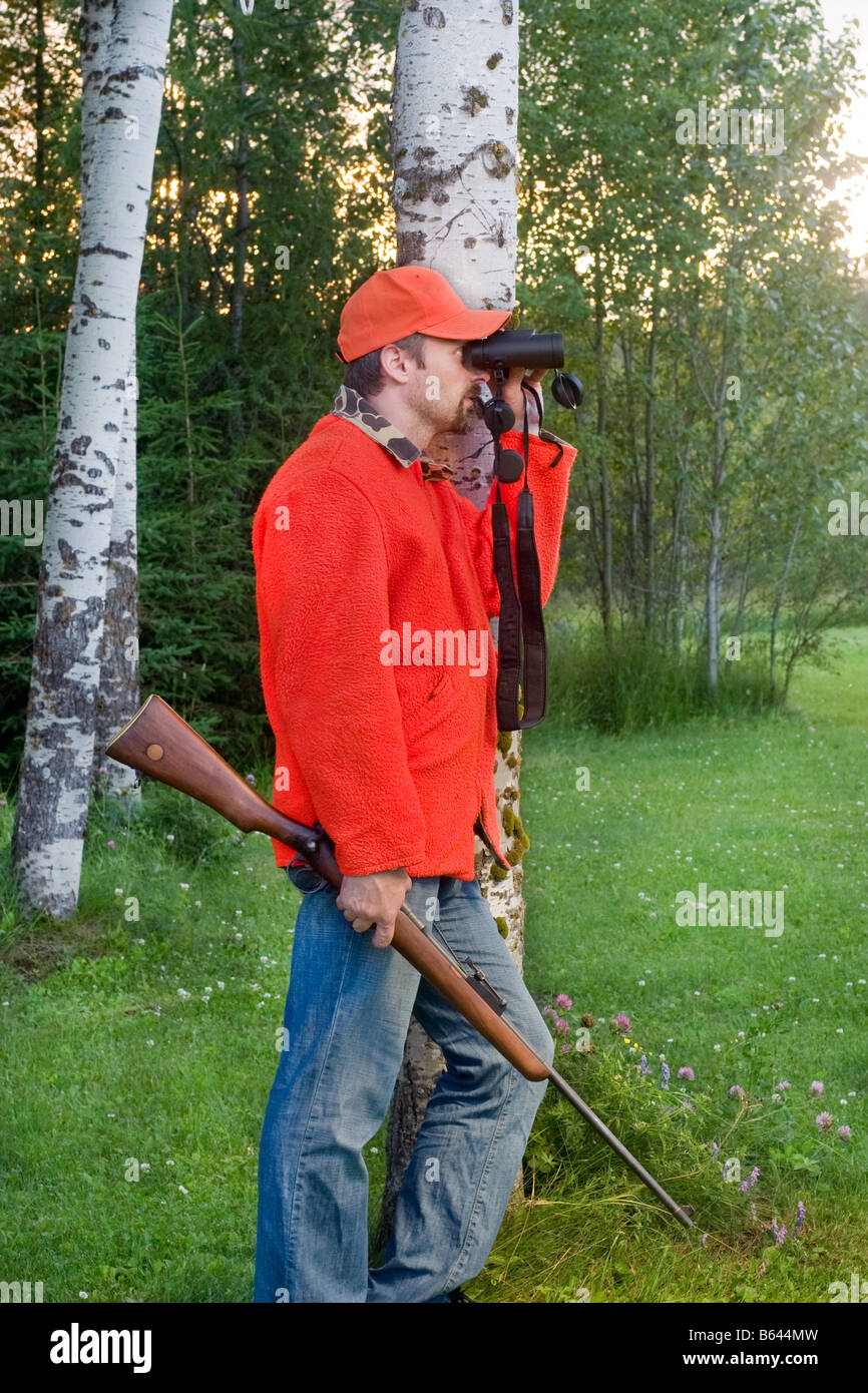 male hunter holding his rifle and looking through binoculars Stock ...