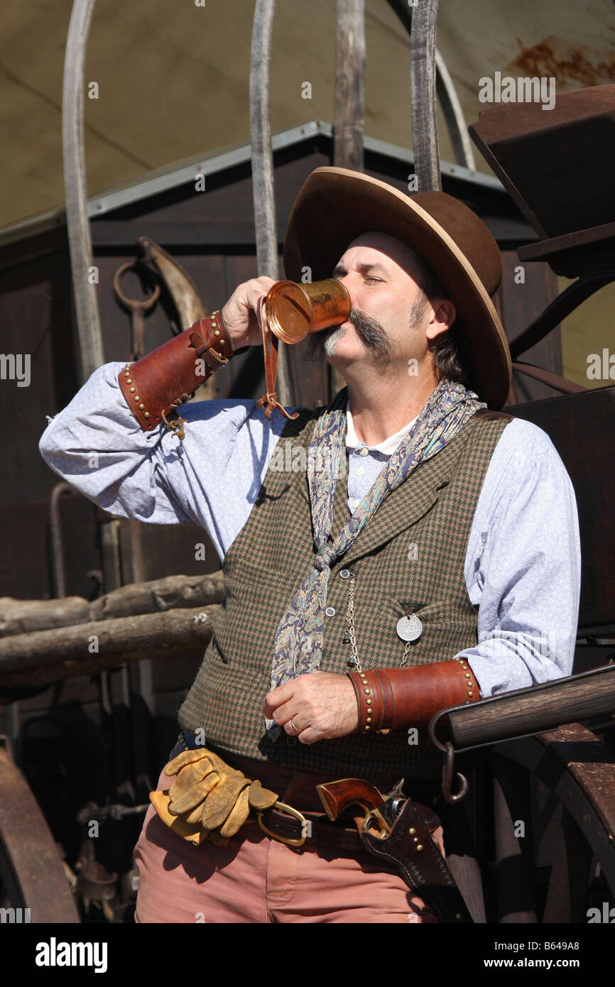 A cowboy leaning on a chuckwagon with his metal cup Stock Photo - Alamy