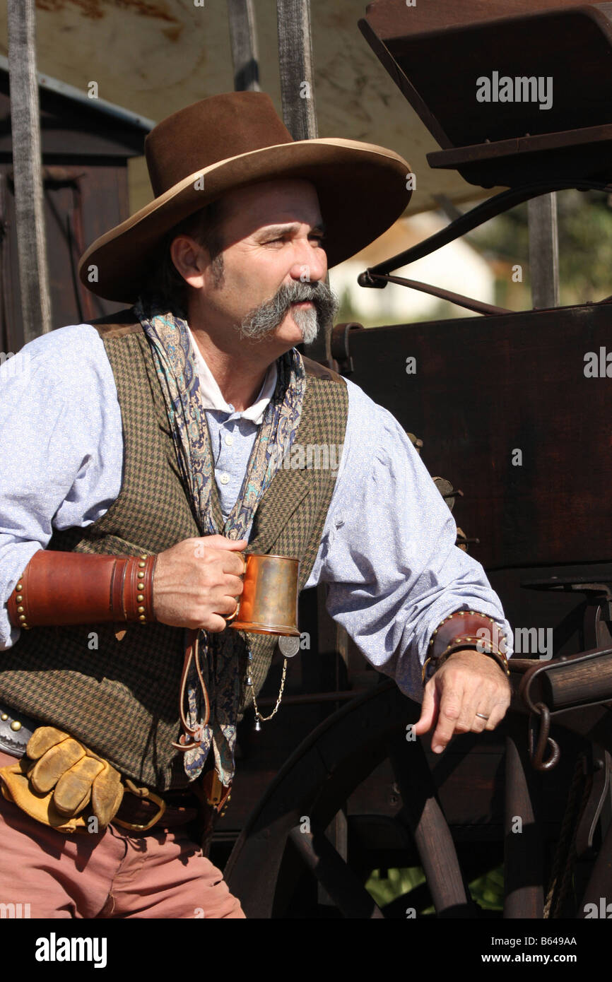 A cowboy leaning on a chuckwagon with his metal cup Stock Photo - Alamy