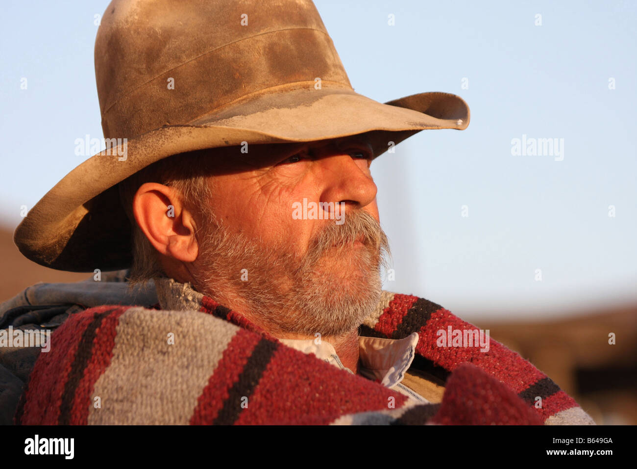 An old timer cowboy leaning against his pack and saddle at sunset Stock ...