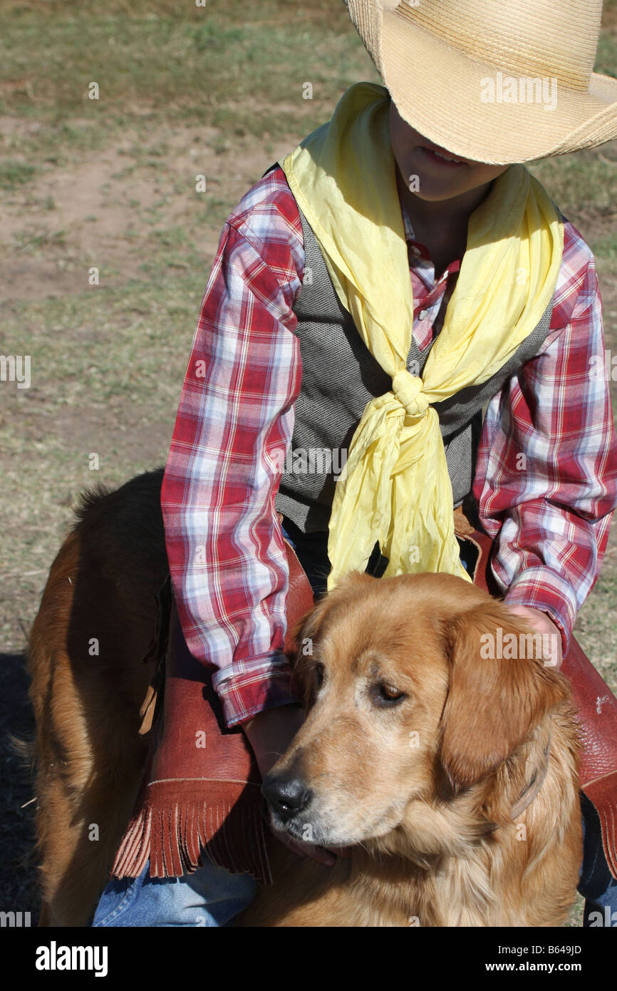 A young boy riding a Golden Retriever dog like a horse by the chuck ...