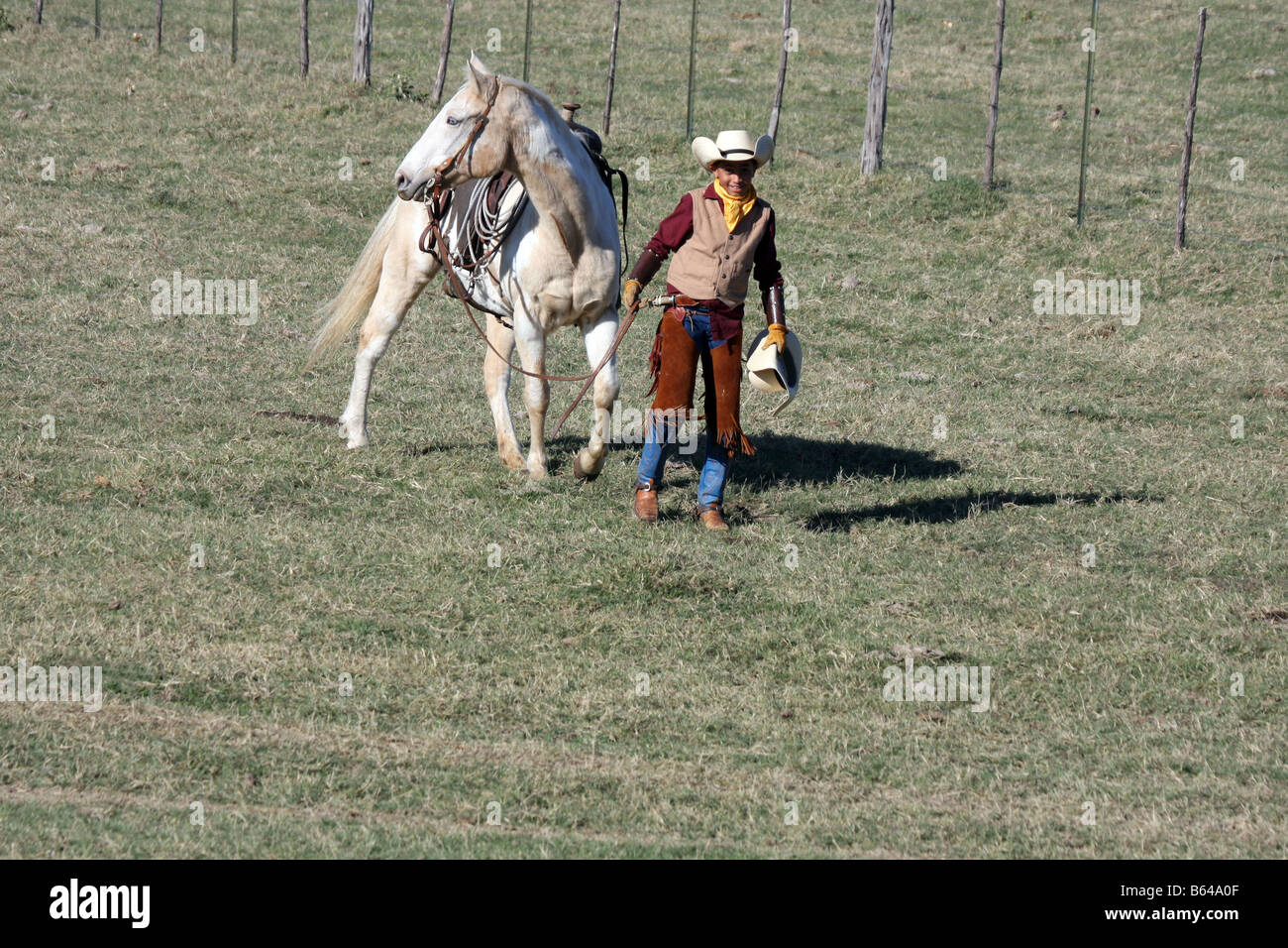A young African American cowboy holding the hat of his dads that fell ...