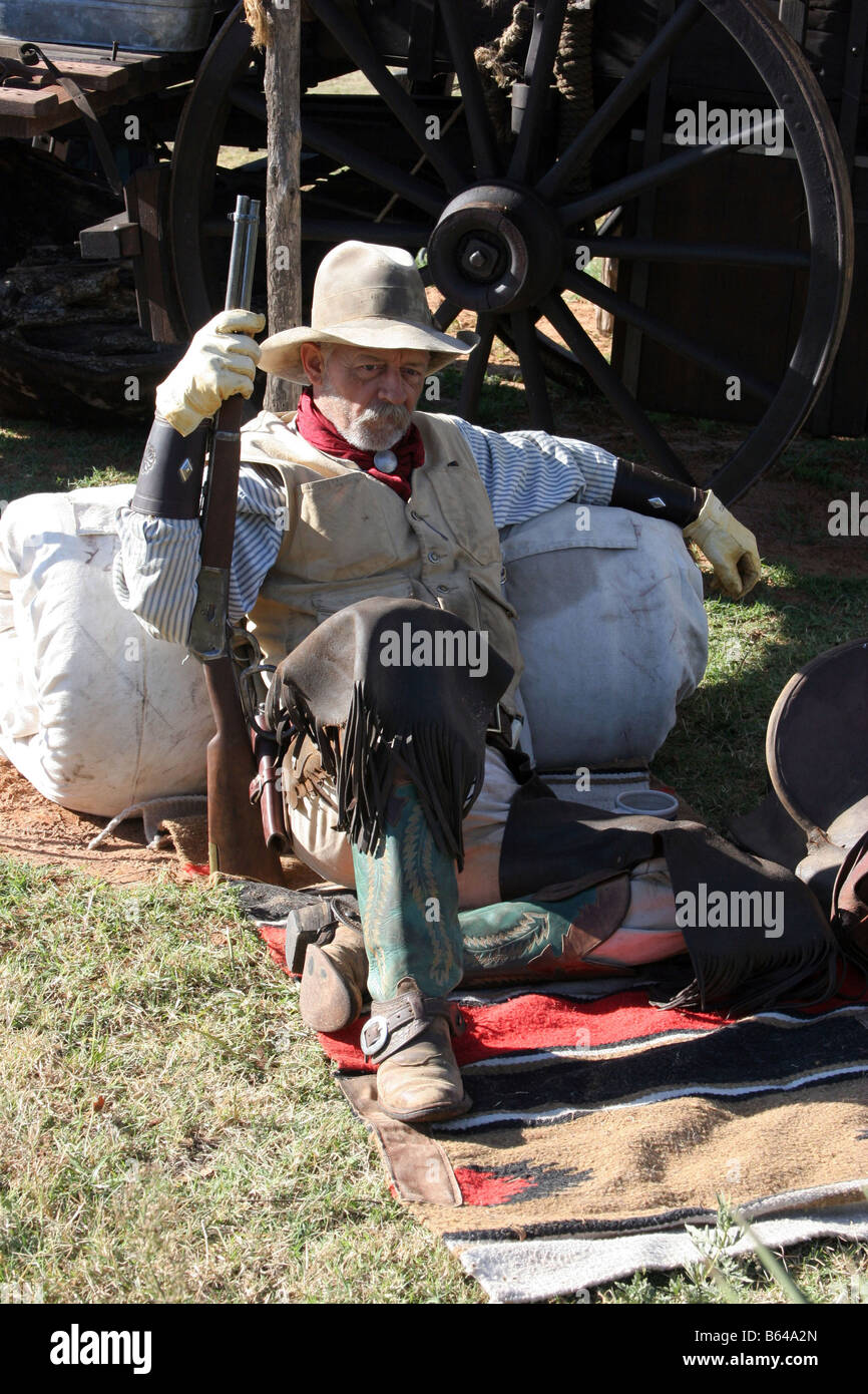 An old timer cowboy leaning against his pack and saddle next to the ...