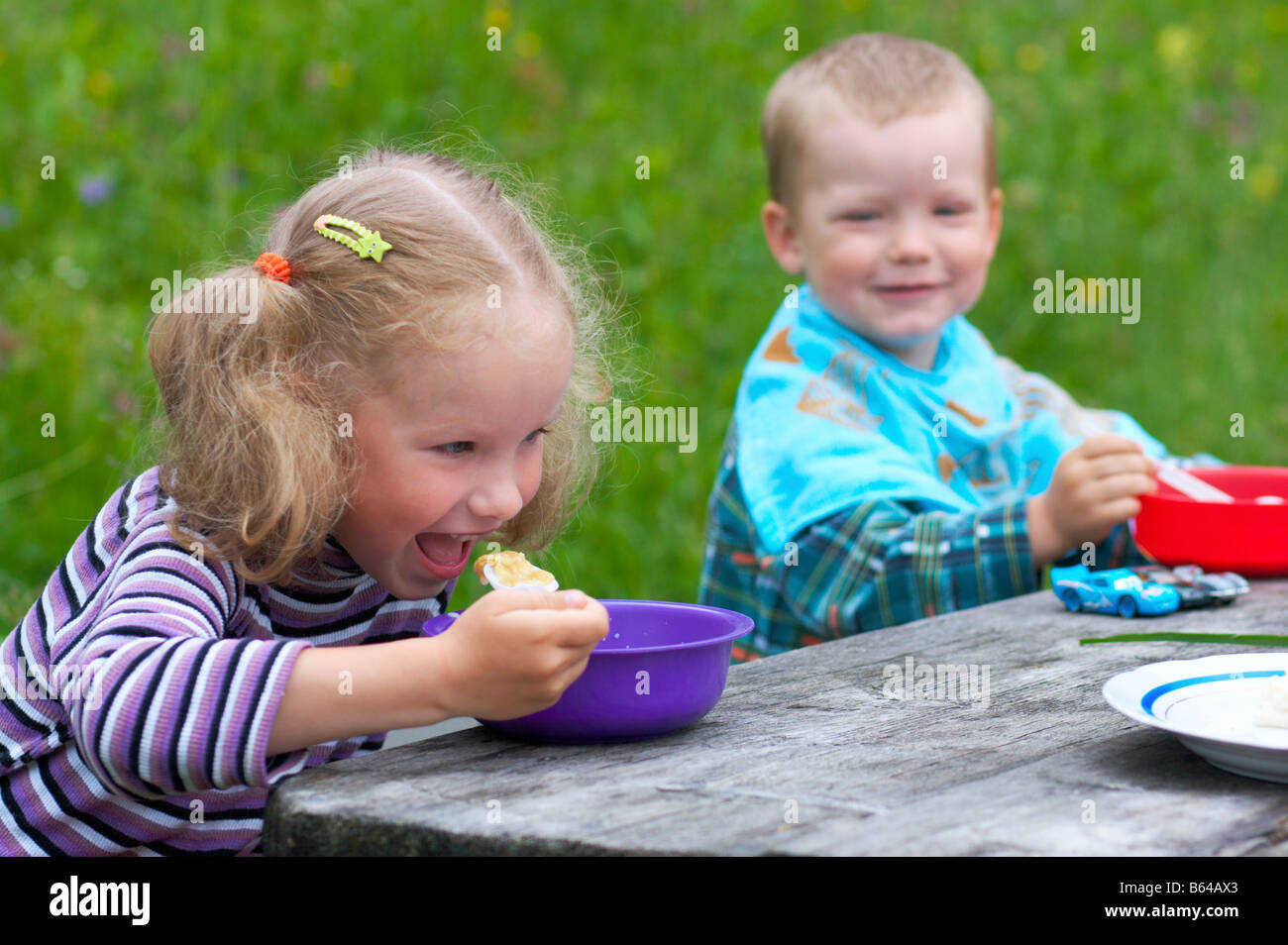 Two small children eating at the wood table outdoors Stock Photo - Alamy