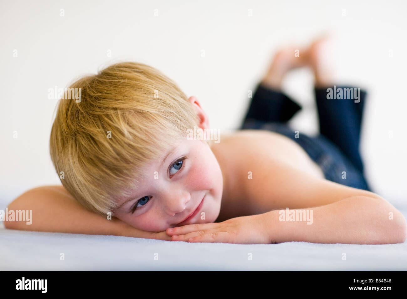 little boy laying on floor smiling, head on arms Stock Photo - Alamy