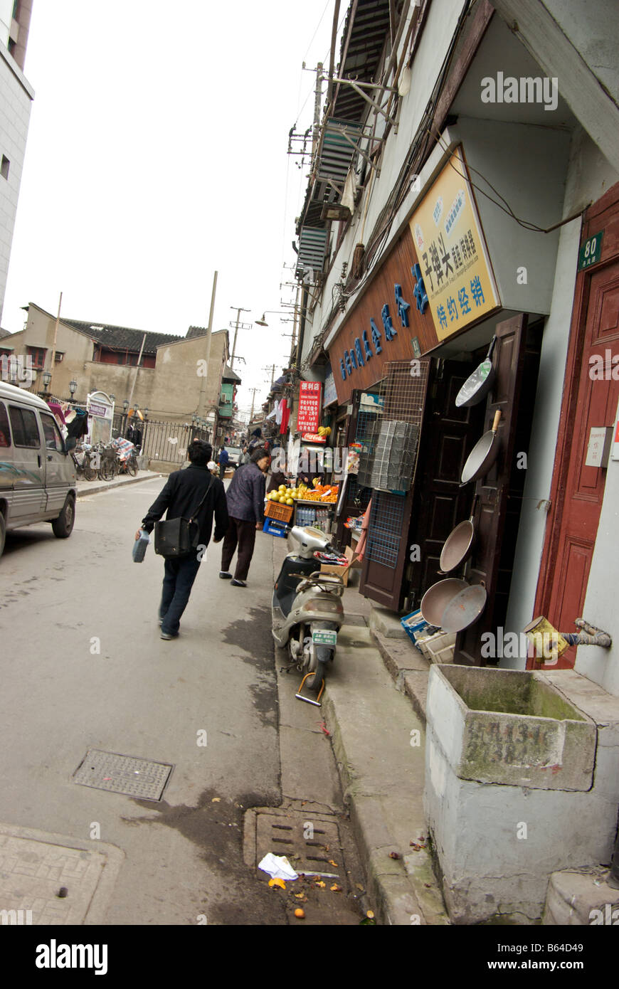 Narrow side street with shoppers and pedestrians looking in hole in the ...