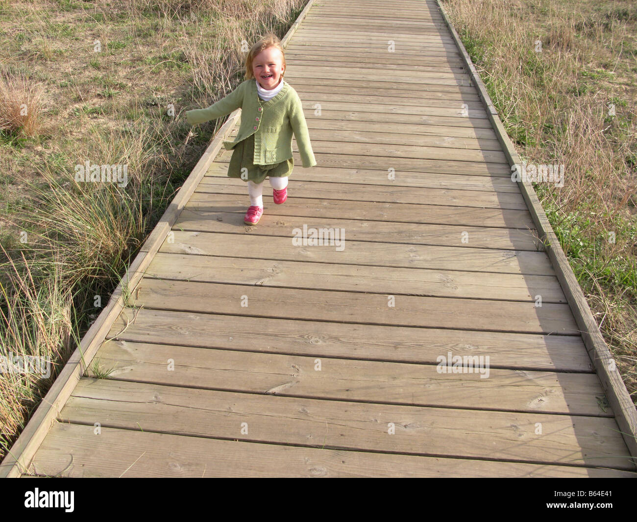 Happy child girl running on wooden path Stock Photo - Alamy