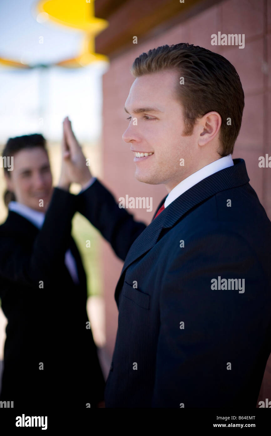 businessman and businesswoman in suits smiling giving high five Stock ...