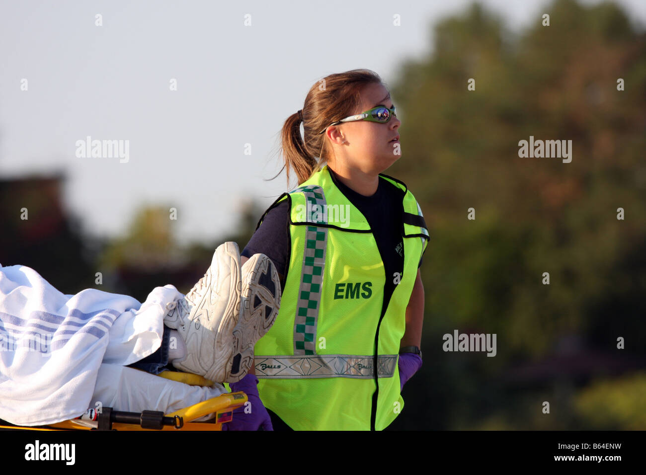 A female EMT walking a stretcher with a patient on board to the ...