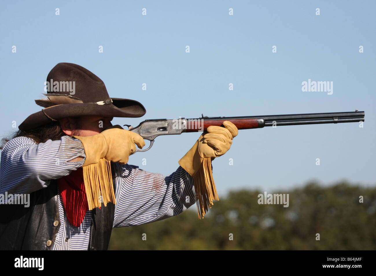 A cowboy taking aim with his rifle on horseback in the old west Stock ...