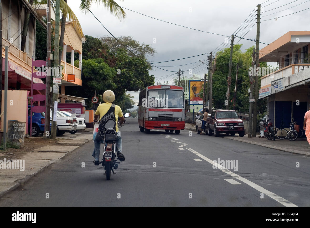 Street scene in Mauritius with motorcycle bus and colourful buildings ...