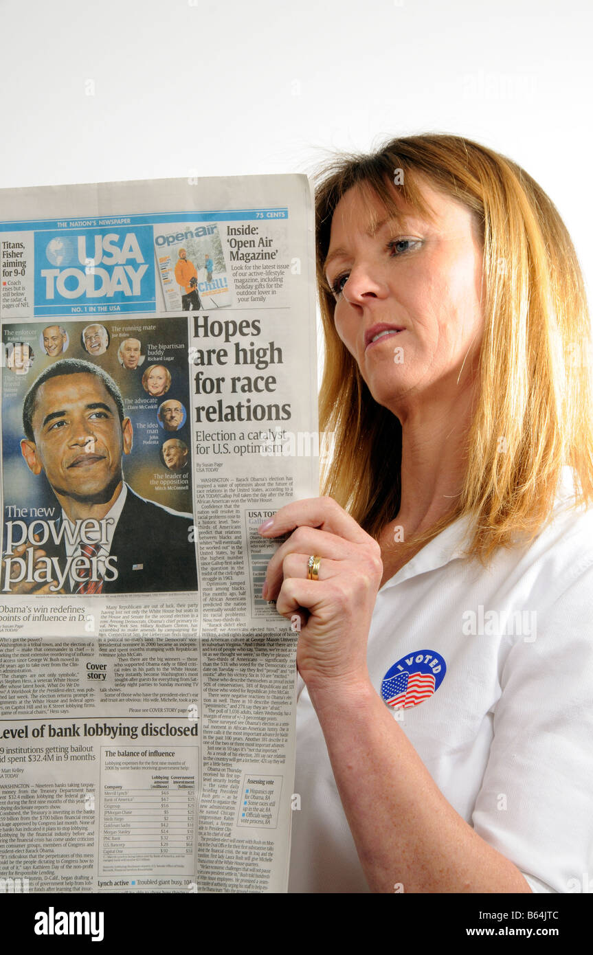 Woman wearing I voted badge reading newspaper showing Barack Obama ...