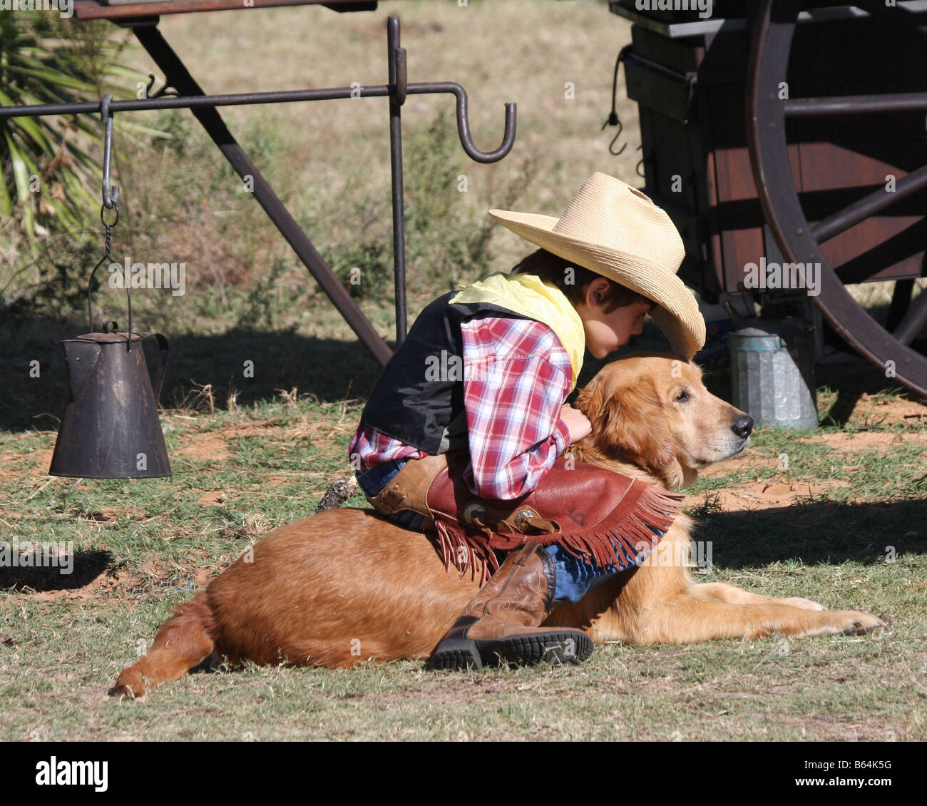 A young boy riding a Golden Retriever dog like a horse by the chuck ...