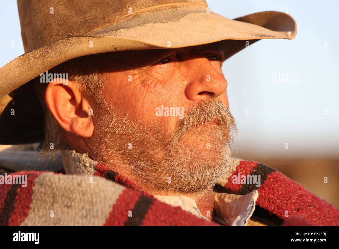 An old timer cowboy leaning against his pack and saddle at sunset Stock ...