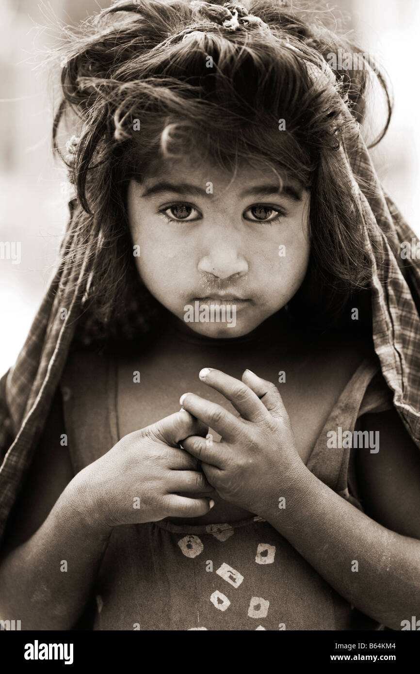 Forlorn looking Poor young Indian girl carrying bag on her head. Sepia ...