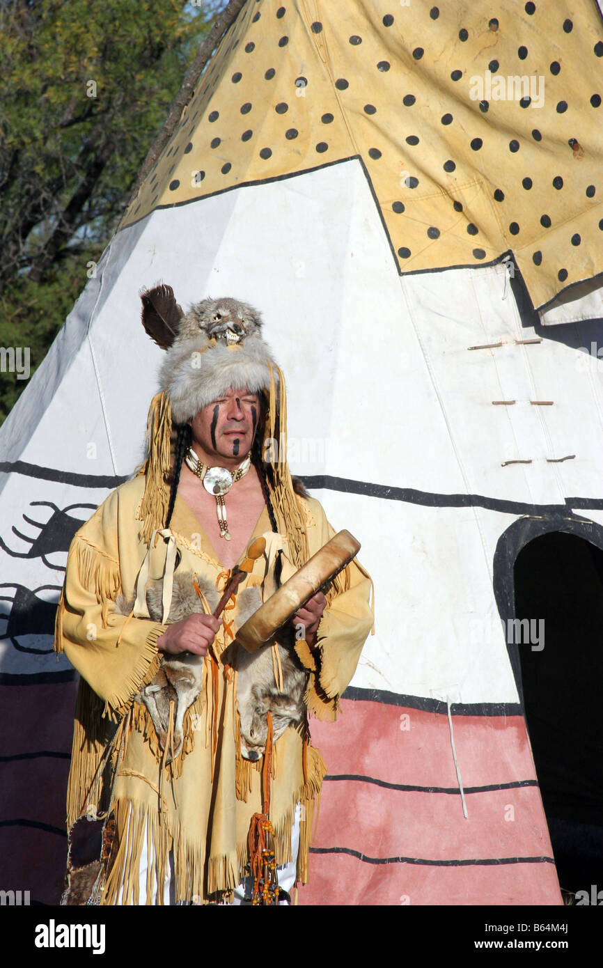 An Apache Native American Indian beating his drum in front of his tipi ...