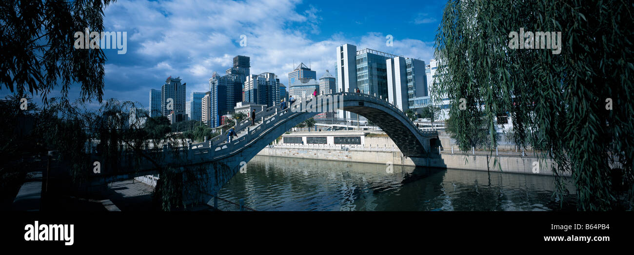 Traditional arch bridge over Tonghuihe River with backdrop of modern ...