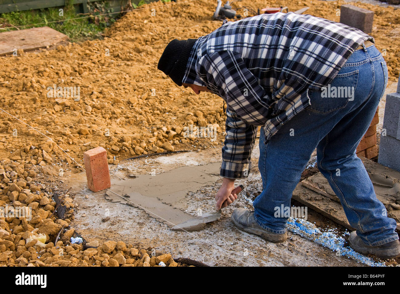 Laying a thin mortar base, ready to mark out the corner of footings for ...