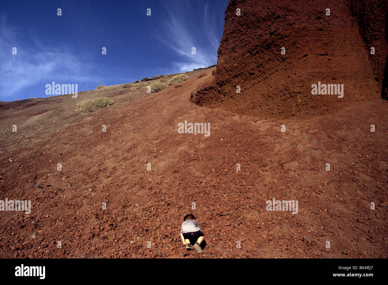 Small child climbing up volcanic slope at Timanfaya National Park ...