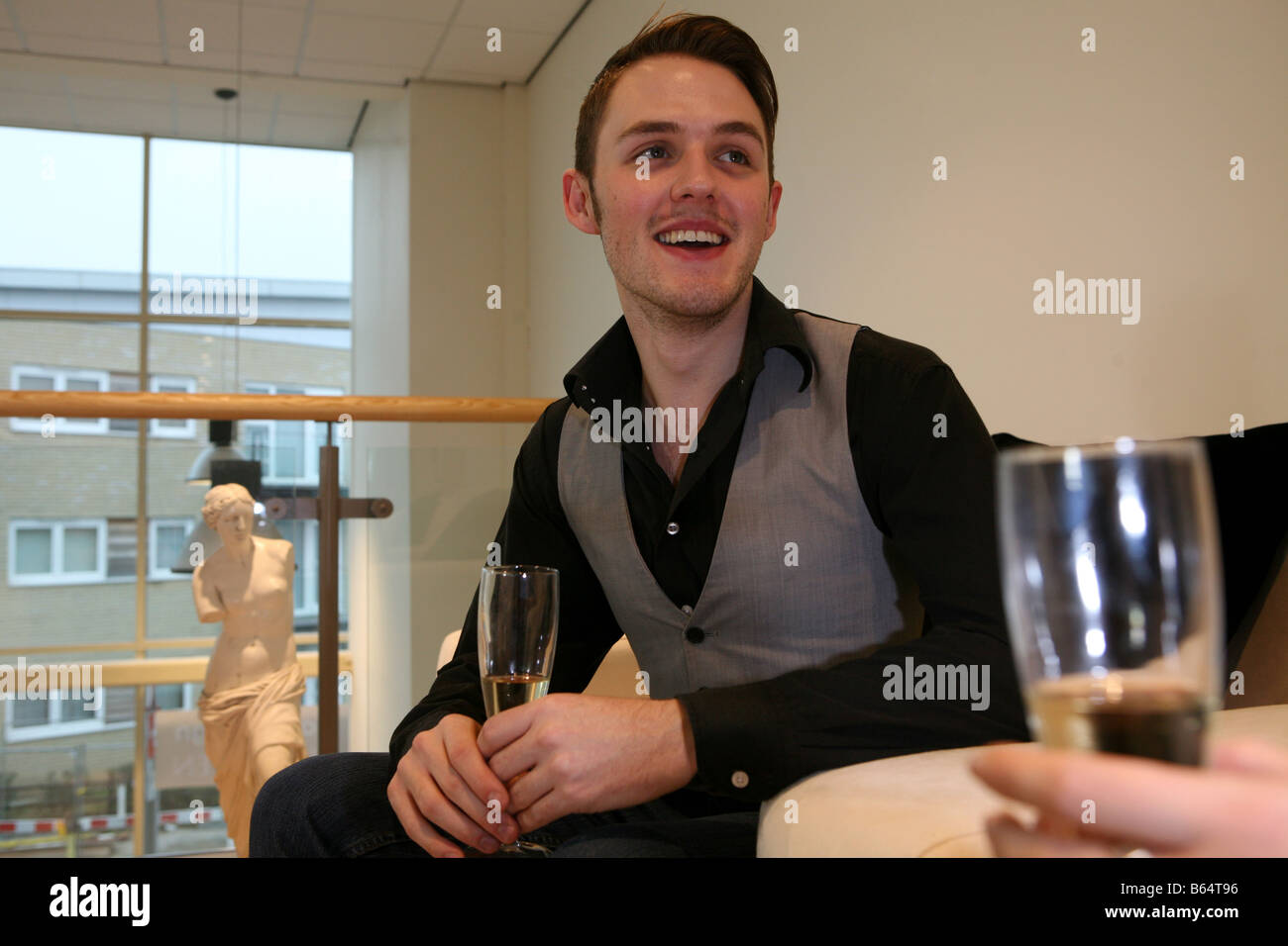 a group of young trendy good looking friends sitting around drinking ...