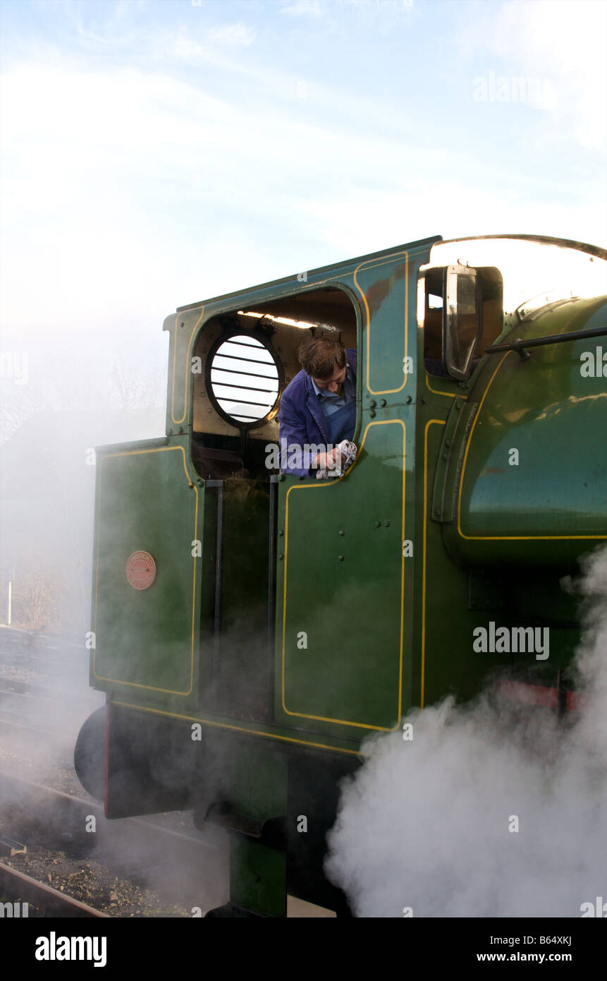 The driver building steam in a tank engine, smoke engulfing the engine ...