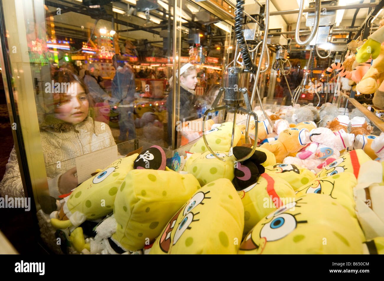 A young girl trying to win a soft toy prize on a fairground amusement ...