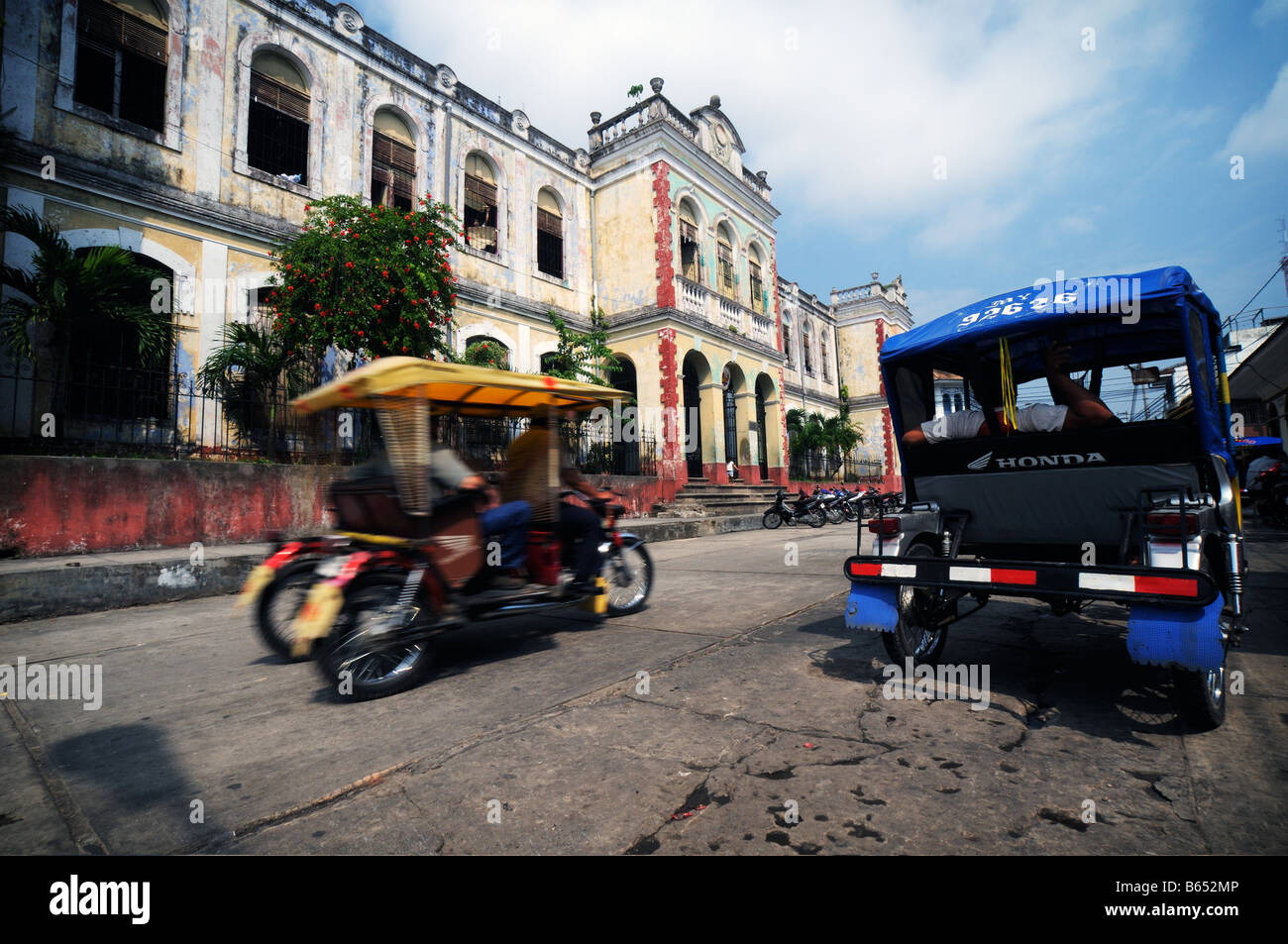 Two moto-taxis in front of a rubber boom era building in Iquitos, Peru ...