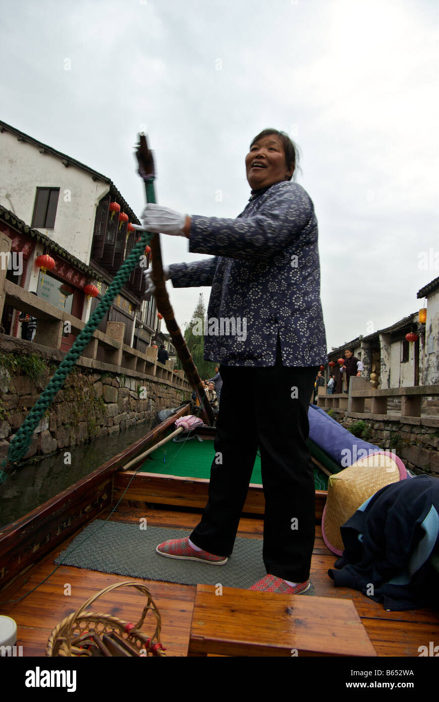 Female gondolier energetically singing sculling her gondola along one ...
