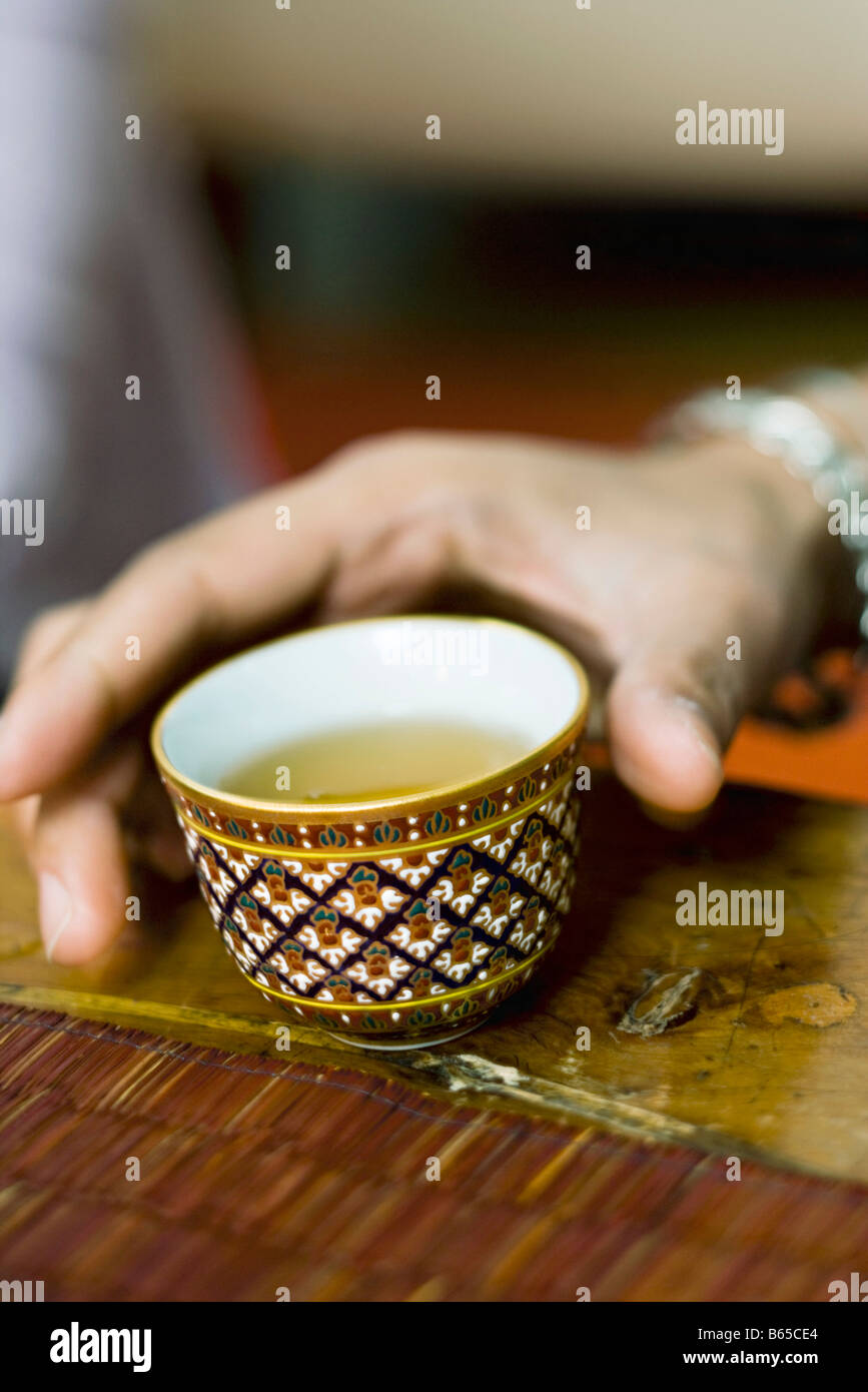 Hand reaching for colorful tea cup full of tea Stock Photo - Alamy