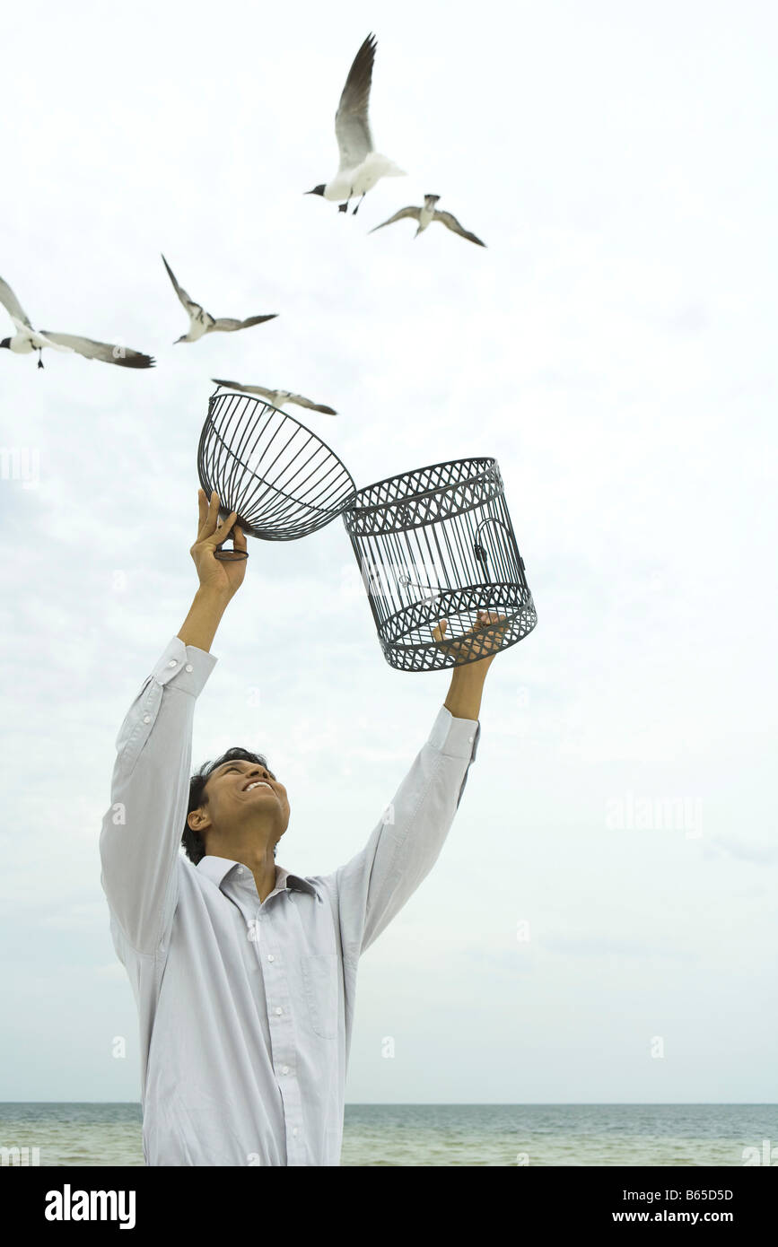 Man releasing bird outdoors, open cage in hand Stock Photo - Alamy
