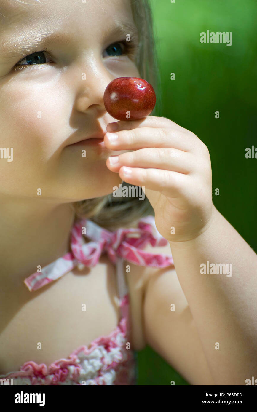 Little girl smelling ripe cherry Stock Photo - Alamy