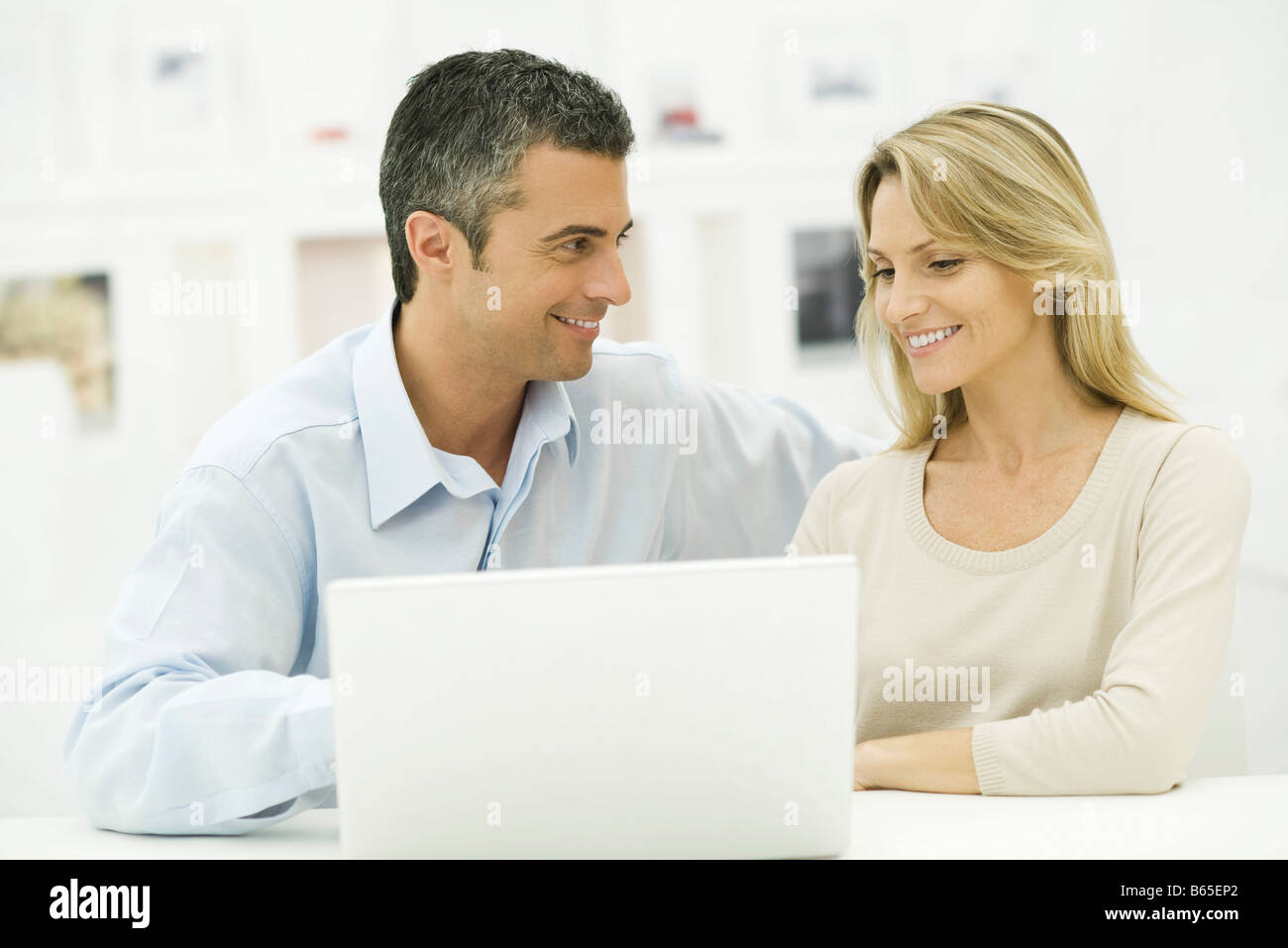 Couple using laptop computer together, smiling Stock Photo - Alamy