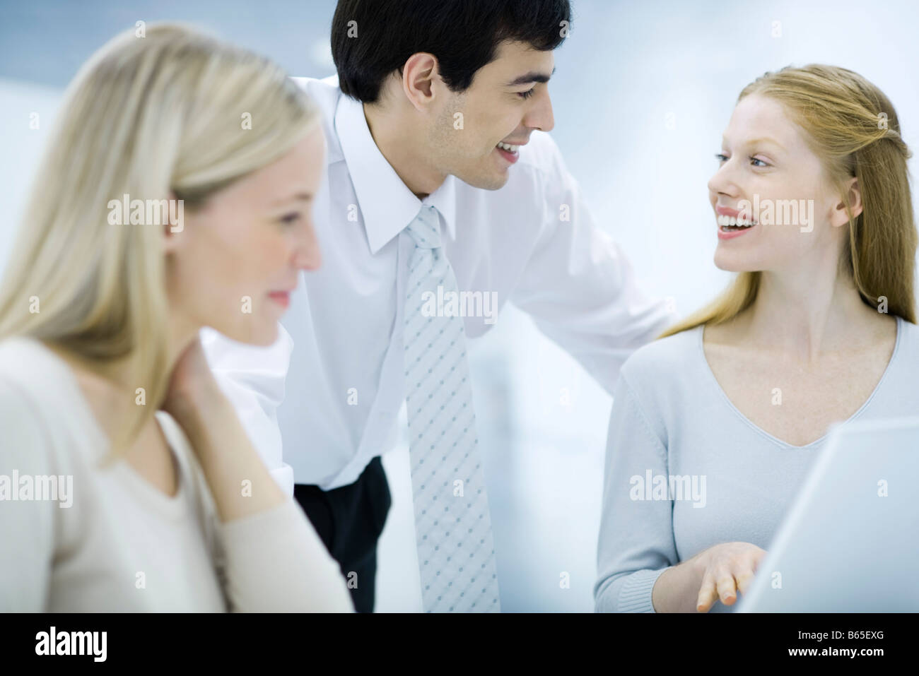Businessman leaning over, chatting with female colleagues Stock Photo ...