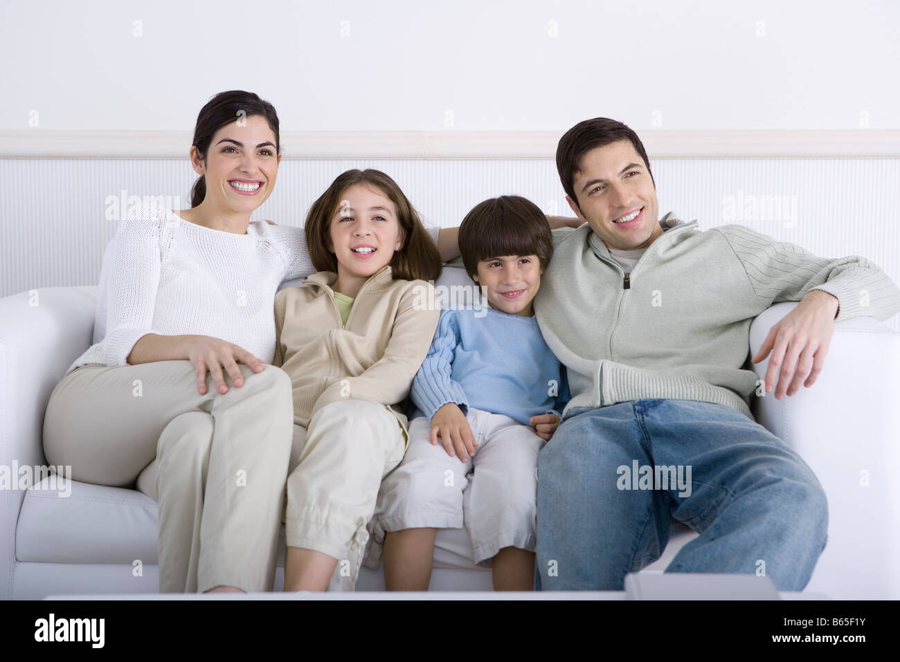 Family sitting together on sofa, looking away Stock Photo - Alamy