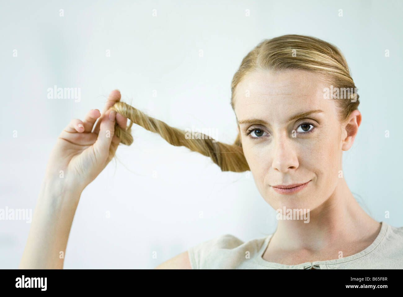 Woman twisting hair, smiling at camera, portrait Stock Photo - Alamy
