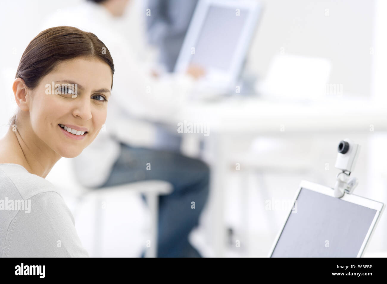 Woman in office, smiling over shoulder at camera Stock Photo - Alamy
