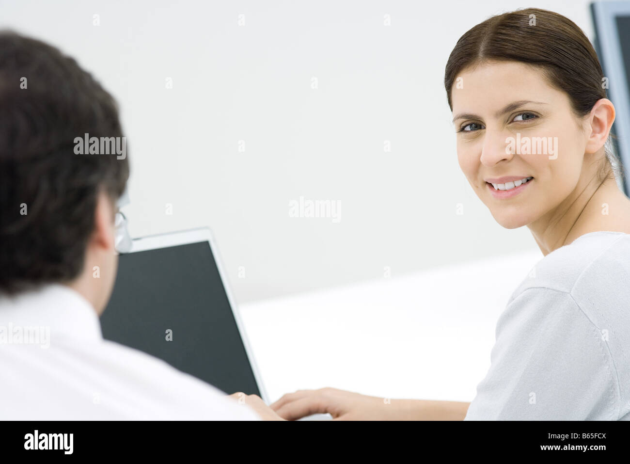 Professional woman in office, smiling over shoulder at camera Stock ...