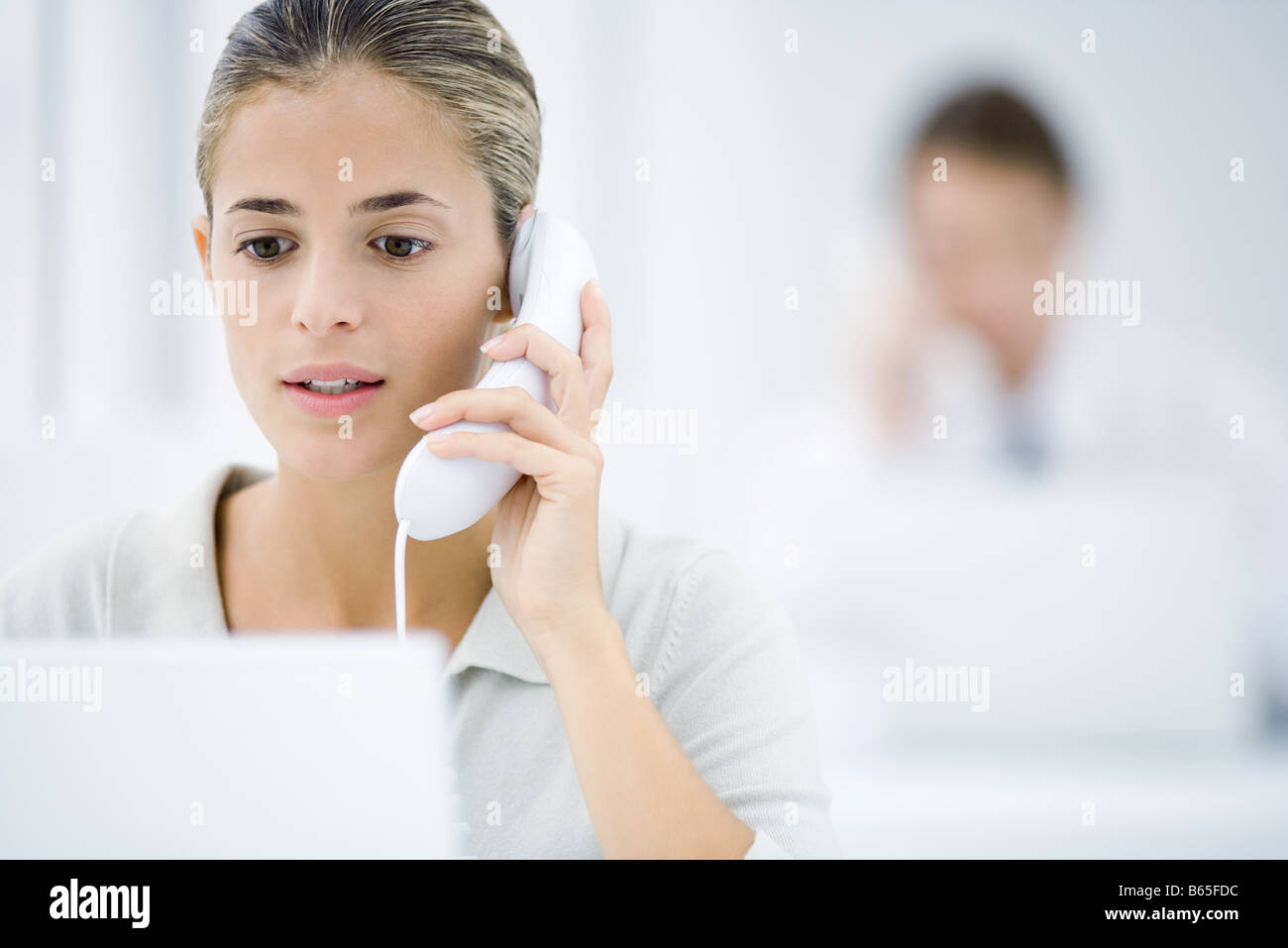Young woman in office, using landline phone Stock Photo - Alamy