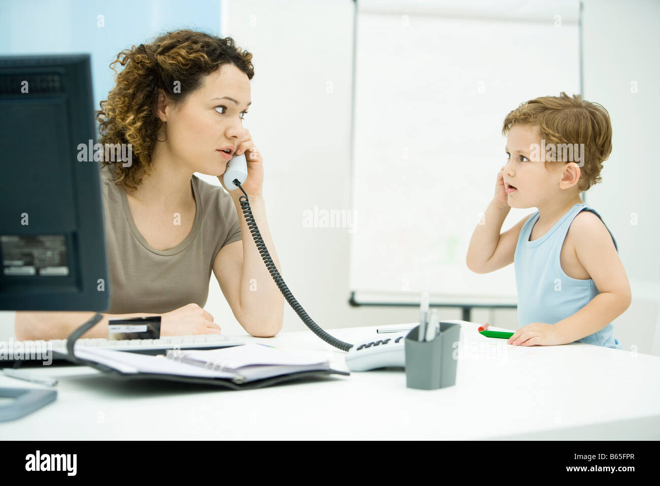 Woman using phone, young son imitating her, looking at each other Stock ...