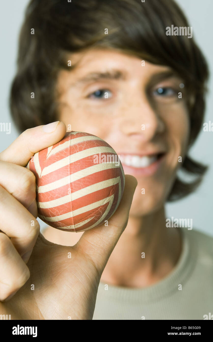Young man holding striped ball, smiling at camera Stock Photo - Alamy
