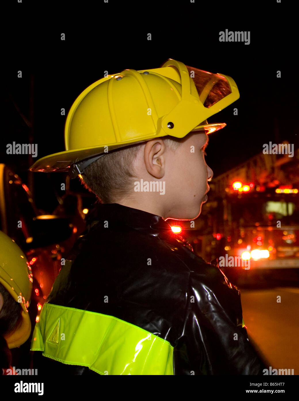 Boy in fireman costume watches fire truck parade Stock Photo - Alamy