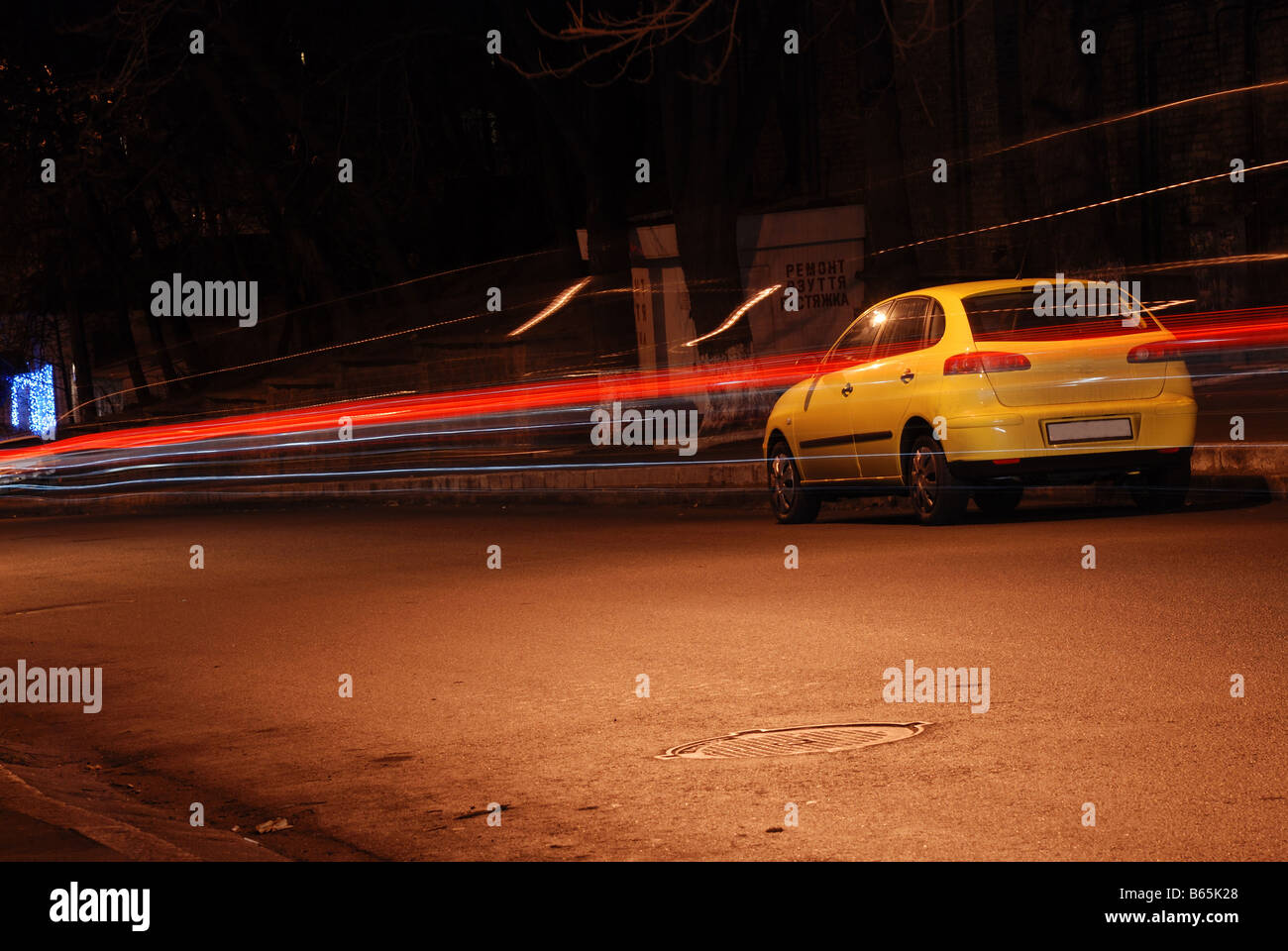 Yellow car in empty night street and bright light red lines of ...