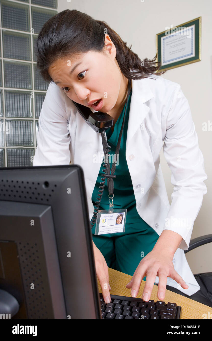 Doctor or nurse looks up patient info on desk top computer Stock Photo ...