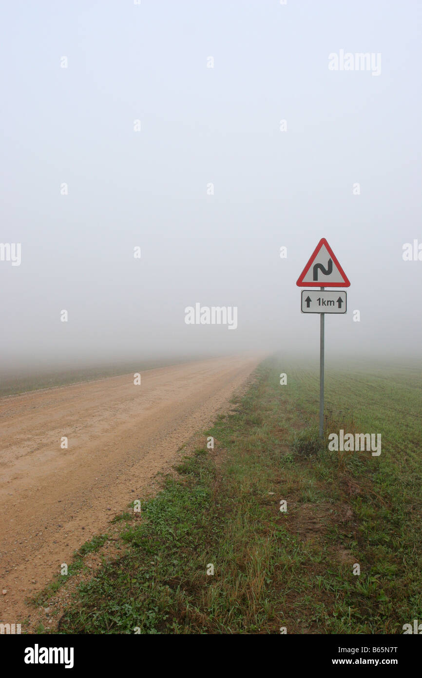 Winding road sign in fog Stock Photo - Alamy