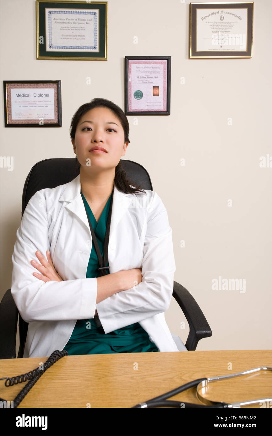 Female doctor sitting in her office with her arms crossed Stock Photo ...