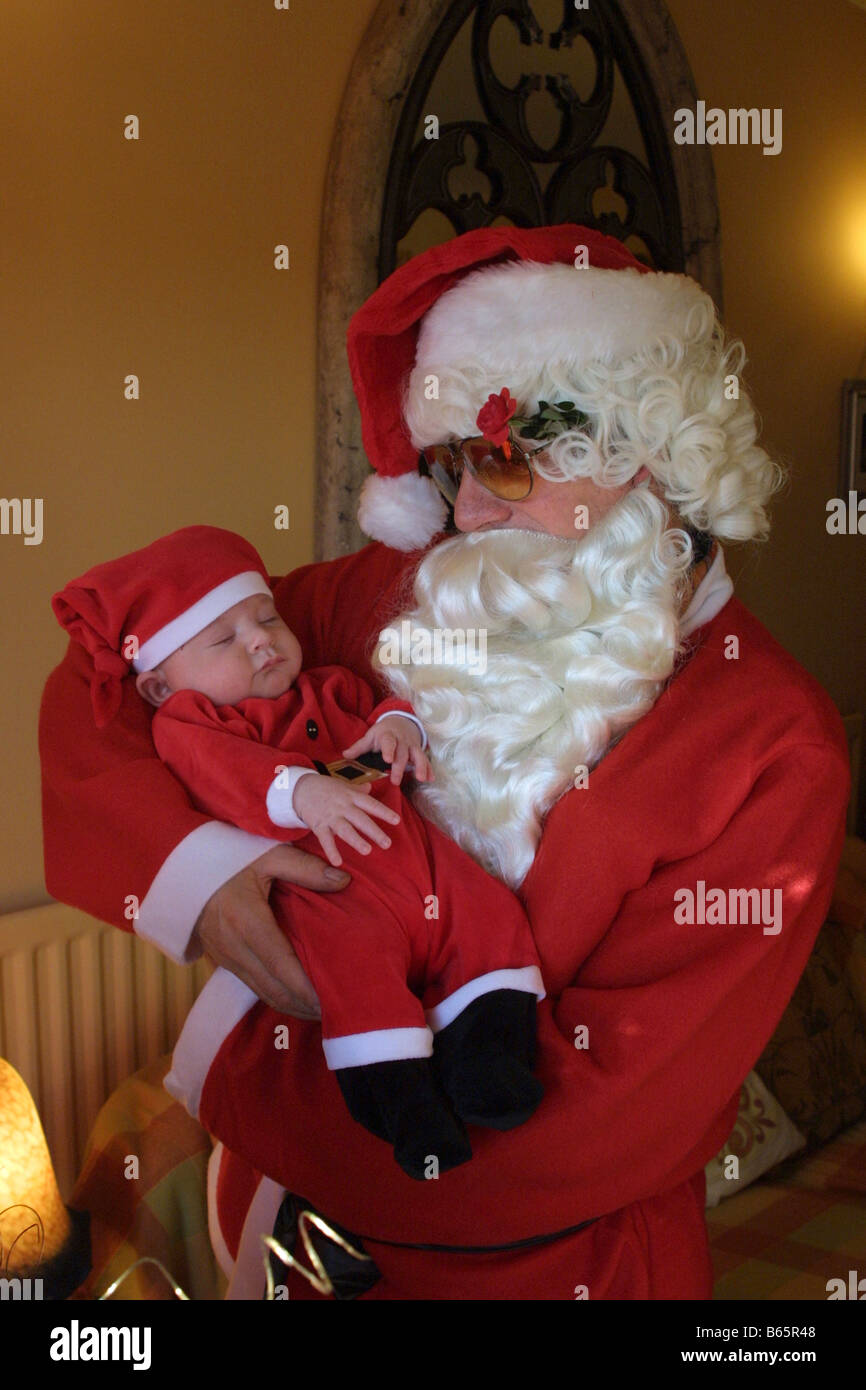 Father Christmas holding baby with red hat. White beard disguise ...