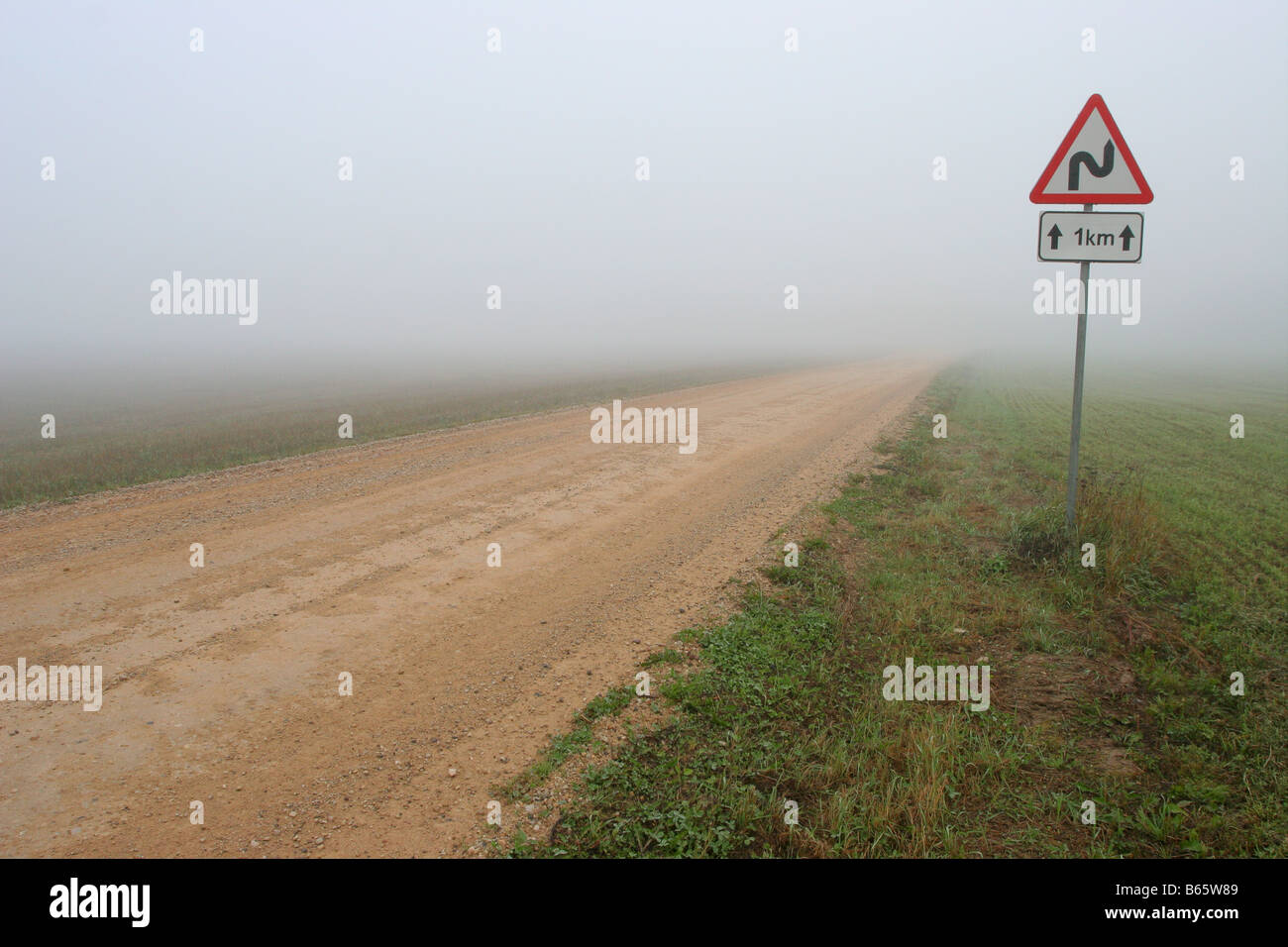 Winding road sign in fog Stock Photo - Alamy