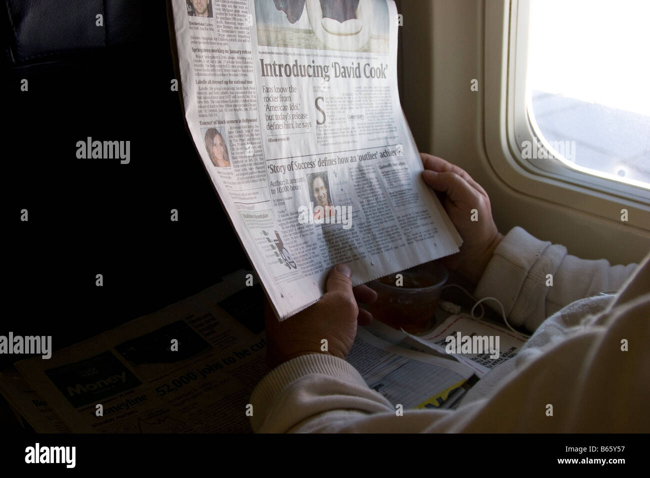 Man reads newspaper on airplane, window seat Stock Photo - Alamy