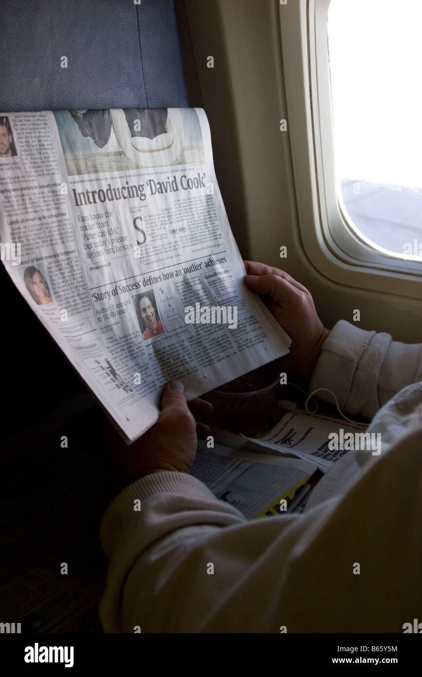 Man reads newspaper on airplane, window seat Stock Photo - Alamy