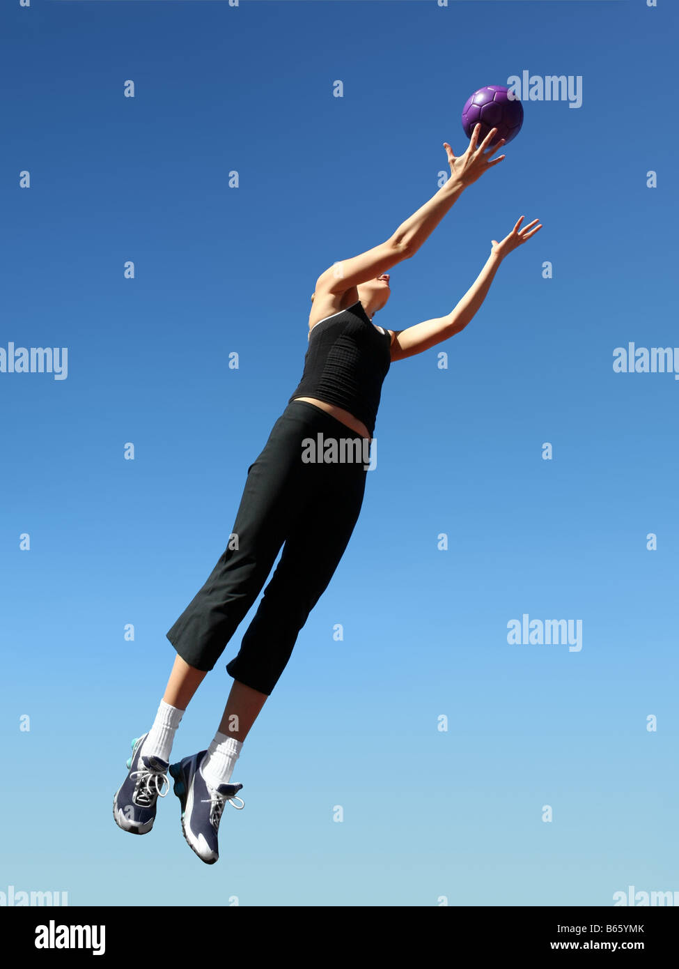 Young woman jumping to catch the ball Stock Photo - Alamy